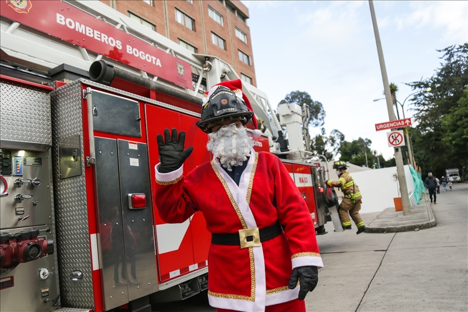 Firefighters dressed as Santa Claus deliver gifts to children at a ...